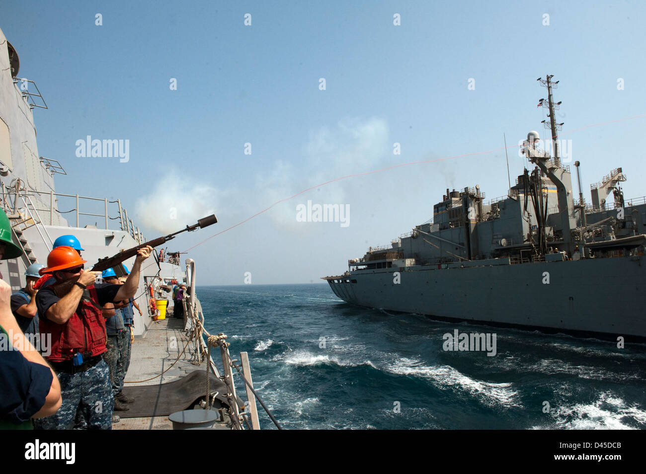 A Sailor aboard a U.S. Navy vessel fires a shot line to initiate a ship ...