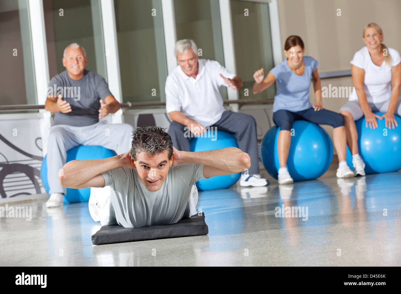 Man doing back exercises in gym with senior people around him Stock ...