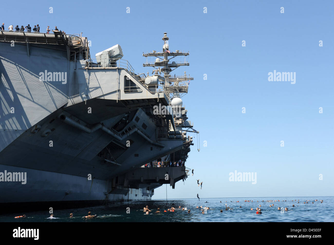 Sailors aboard a U.S. Navy ship jump into the Arabian Sea during a swim ...