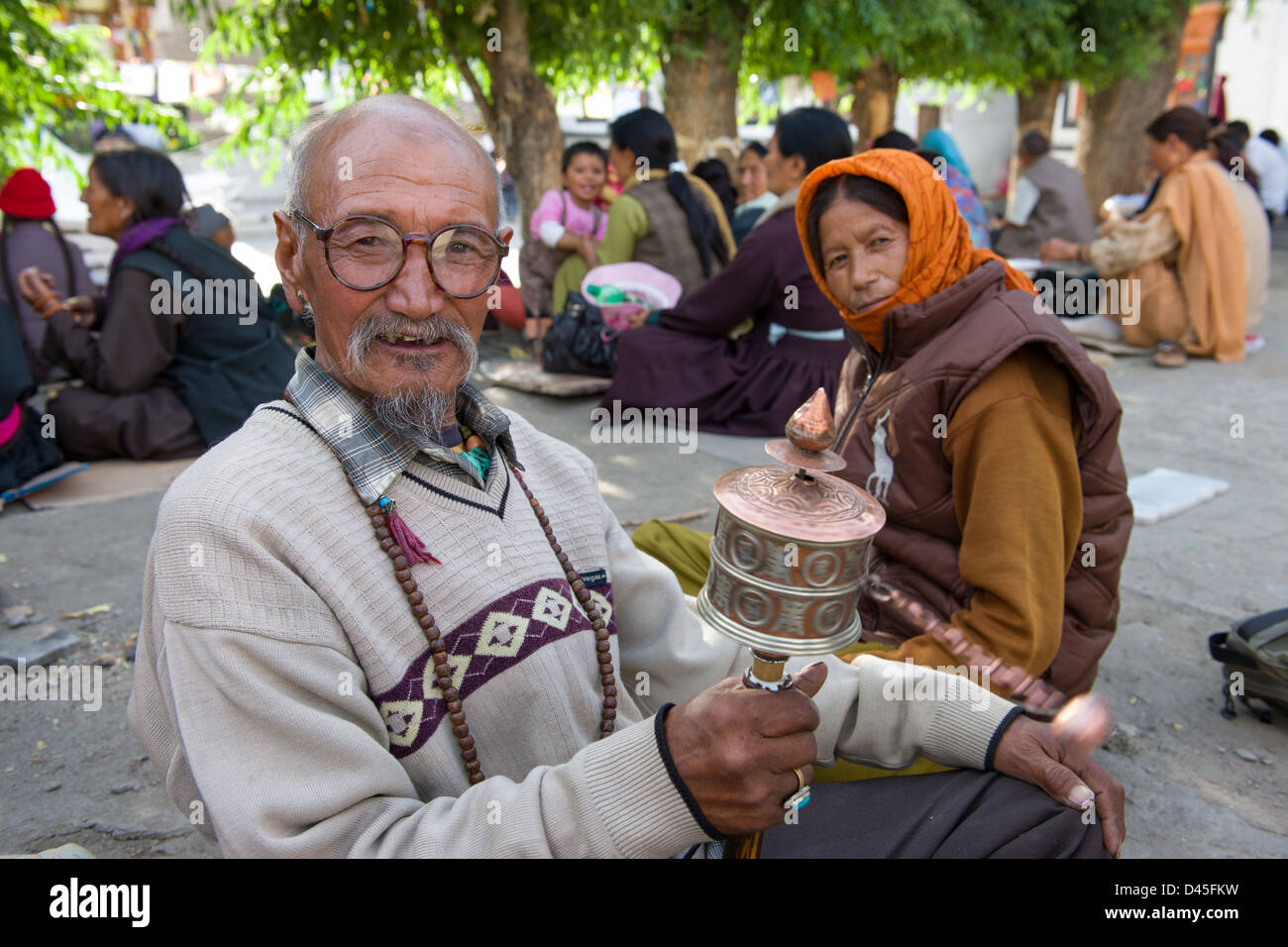 Elderly male pilgrim carrying a prayer wheel, in a group of pilgrims at ...