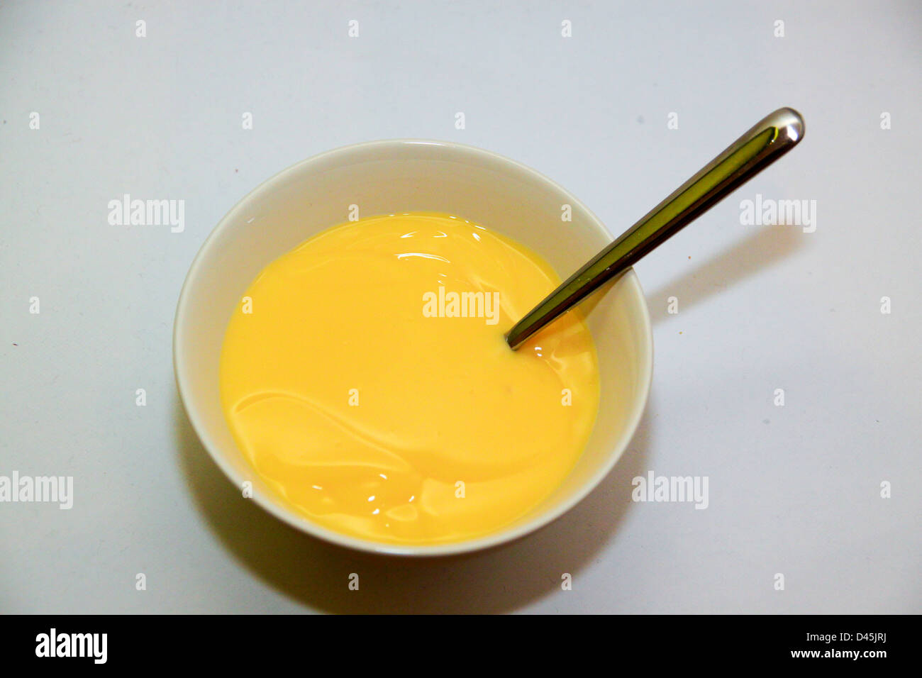 Bowl of custard with spoon Stock Photo - Alamy