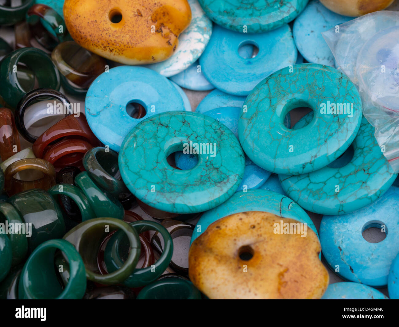 Coloured beads and rings. A display of carved stone beads and rings ...
