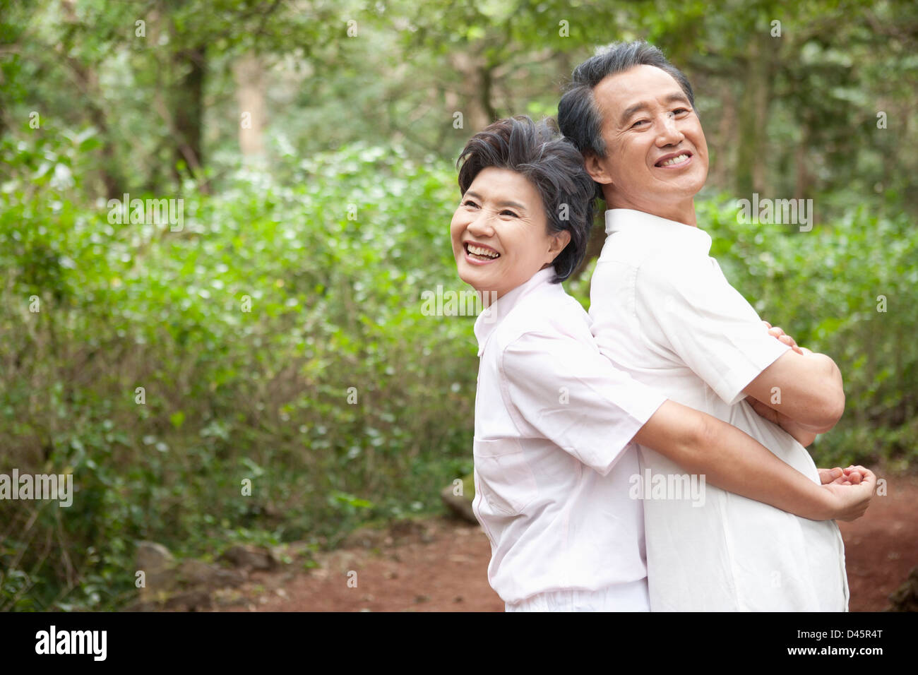 middle age couple in back to back pose in nature Stock Photo - Alamy