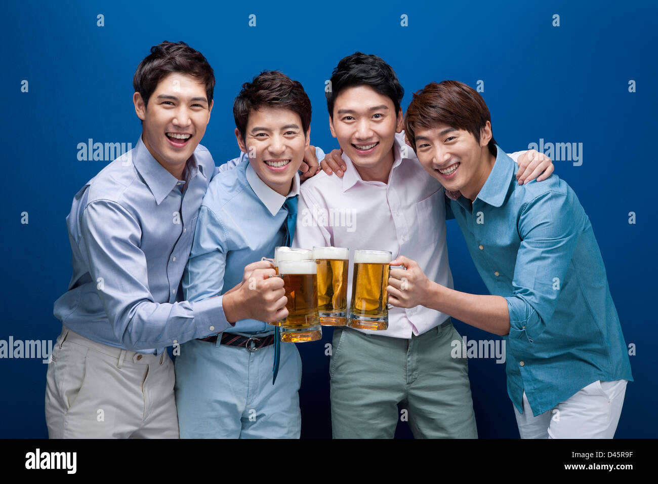 four businessmen looking at camera while toasting with beer Stock Photo ...
