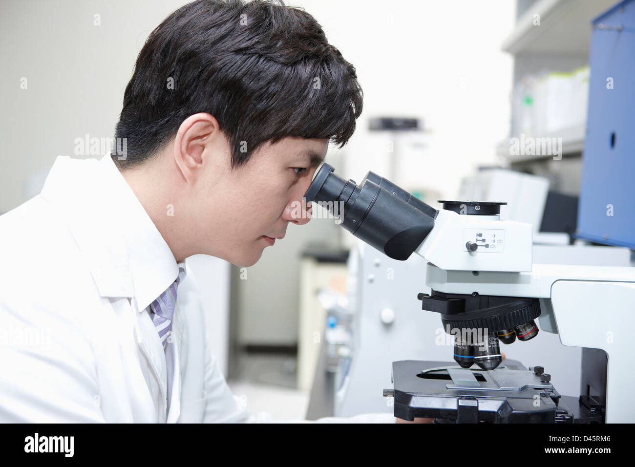 a doctor looking through microscope Stock Photo - Alamy