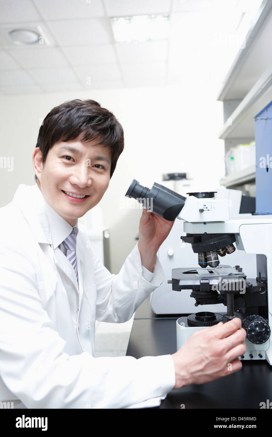 a doctor posing at camera while looking through microscope Stock Photo ...
