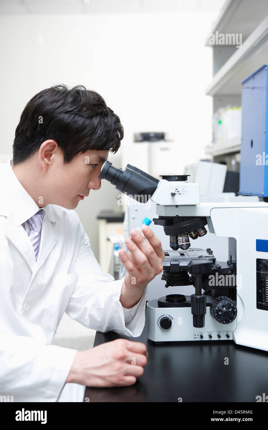 a doctor looking through microscope Stock Photo - Alamy