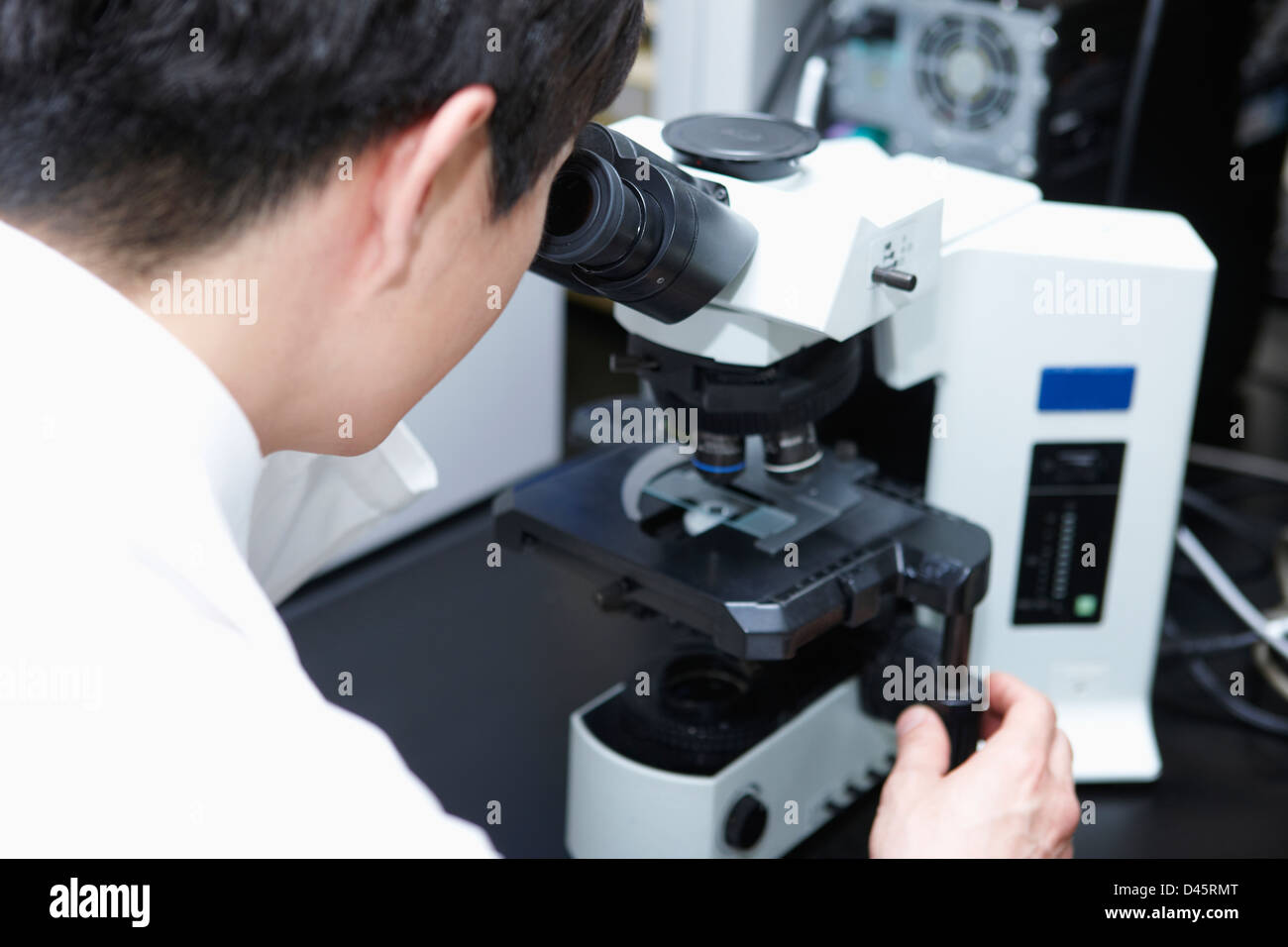 a doctor looking through microscope Stock Photo - Alamy