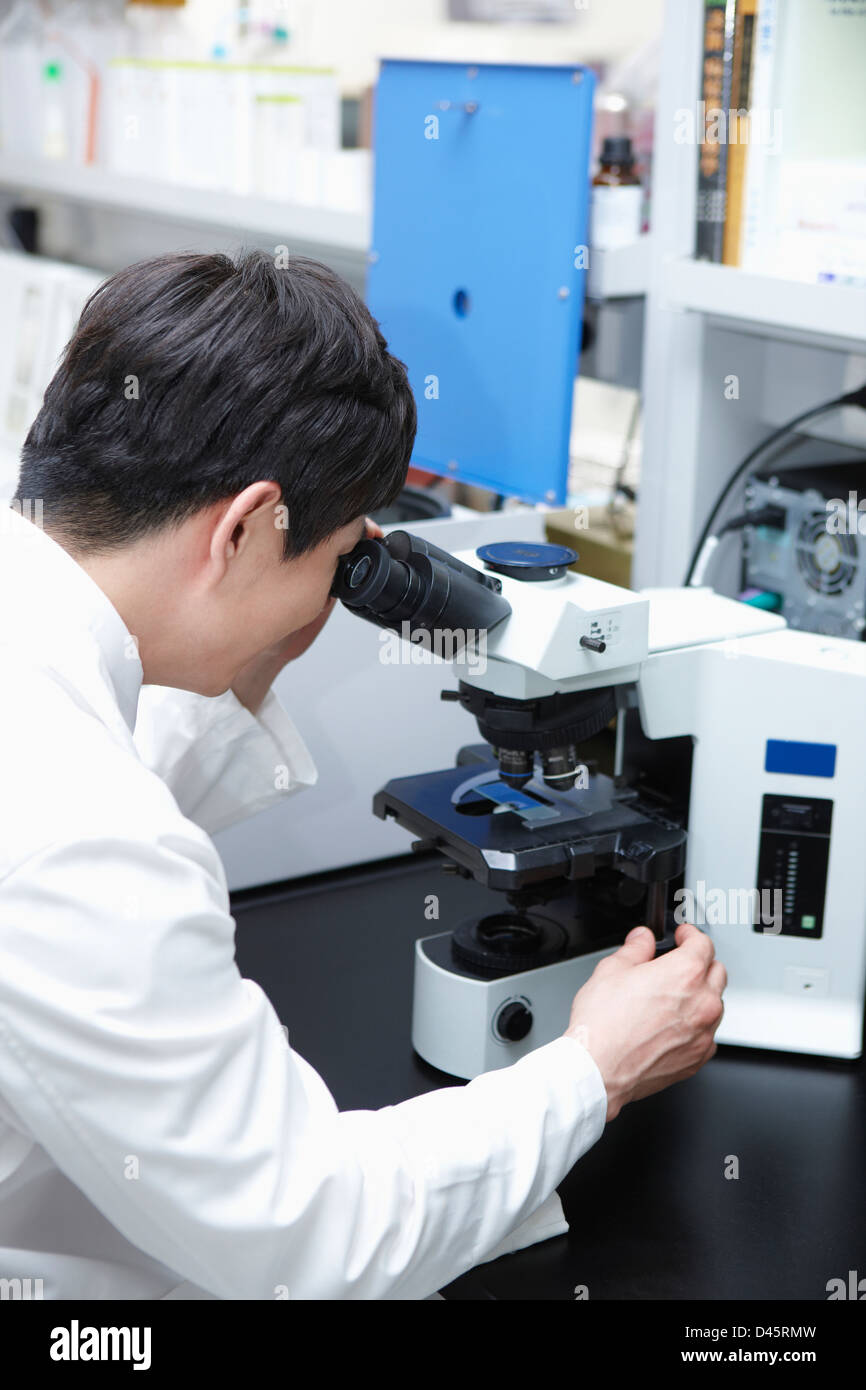 a doctor looking through microscope Stock Photo - Alamy