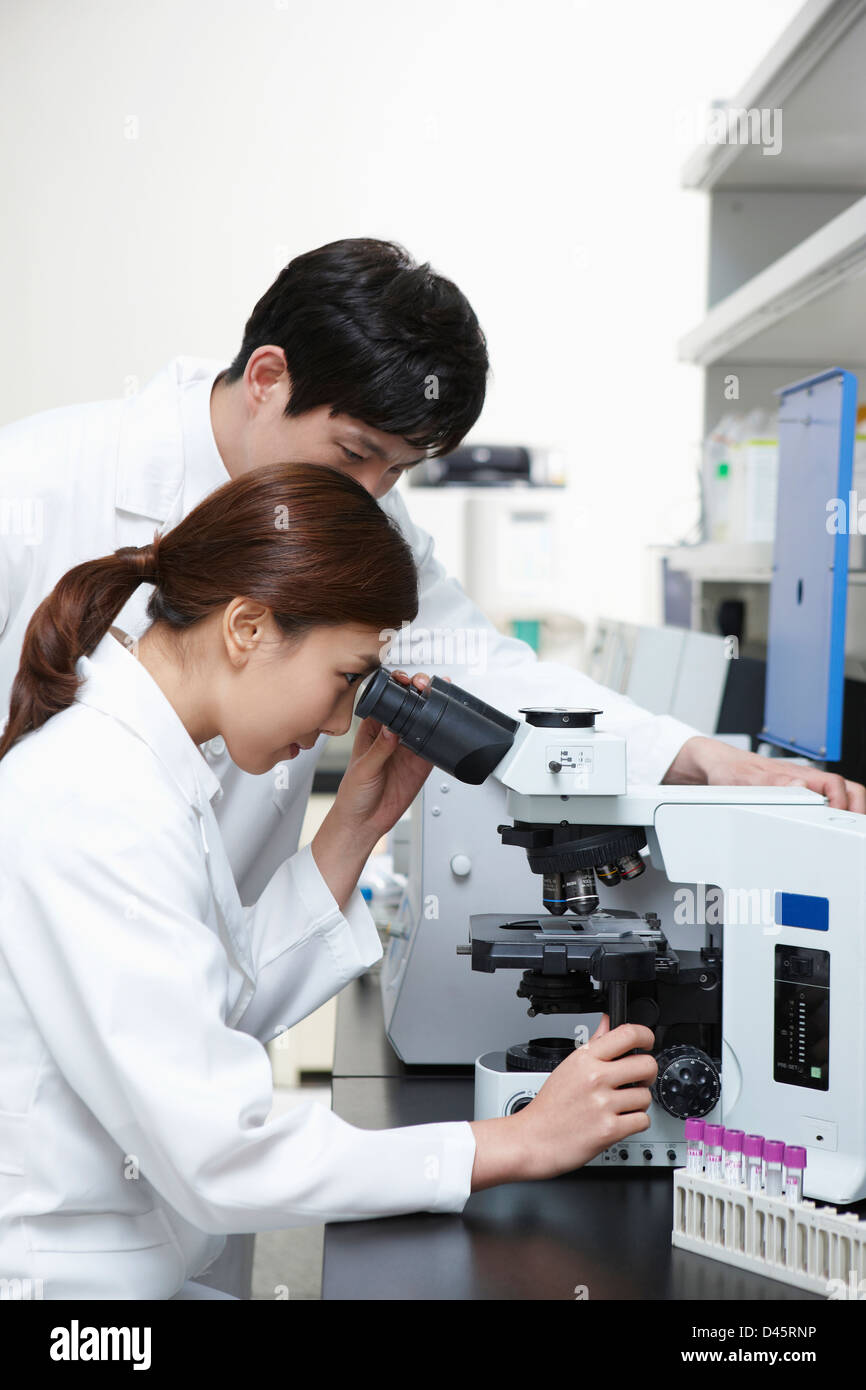 a female doctor looking through microscope Stock Photo - Alamy