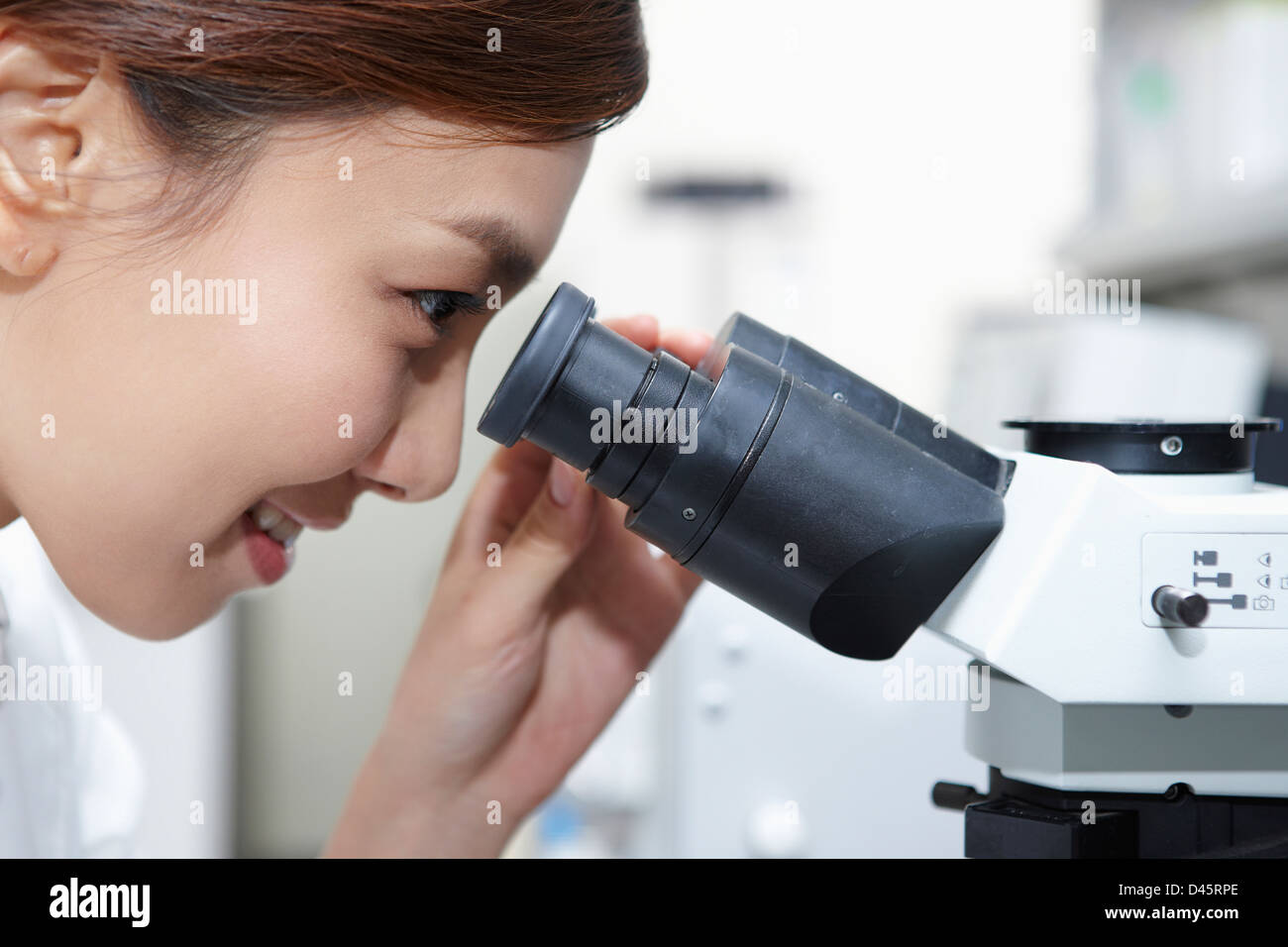 a female doctor looking through a microscope Stock Photo - Alamy