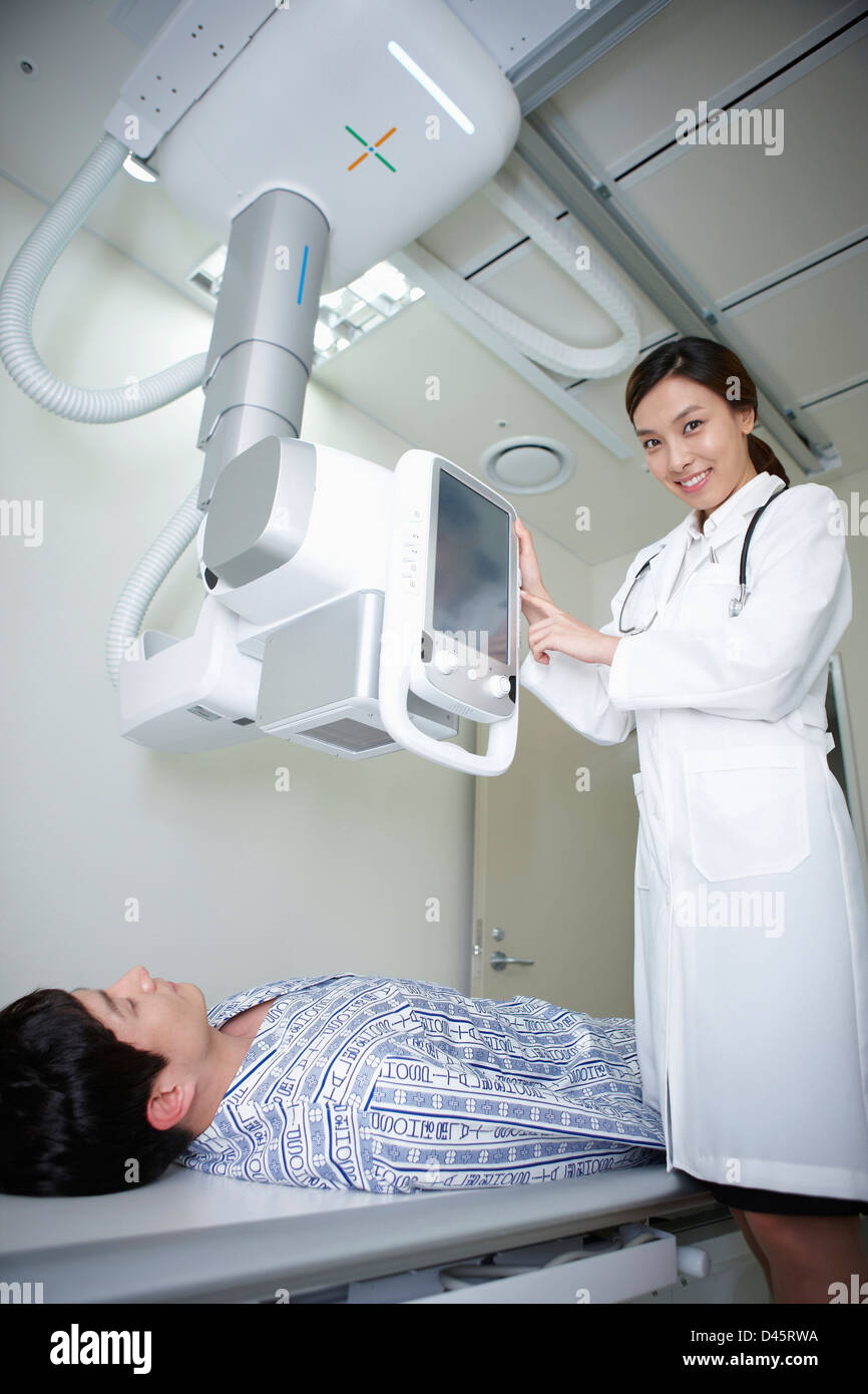 a patient lying on a bed and a doctor using x ray machine Stock Photo ...