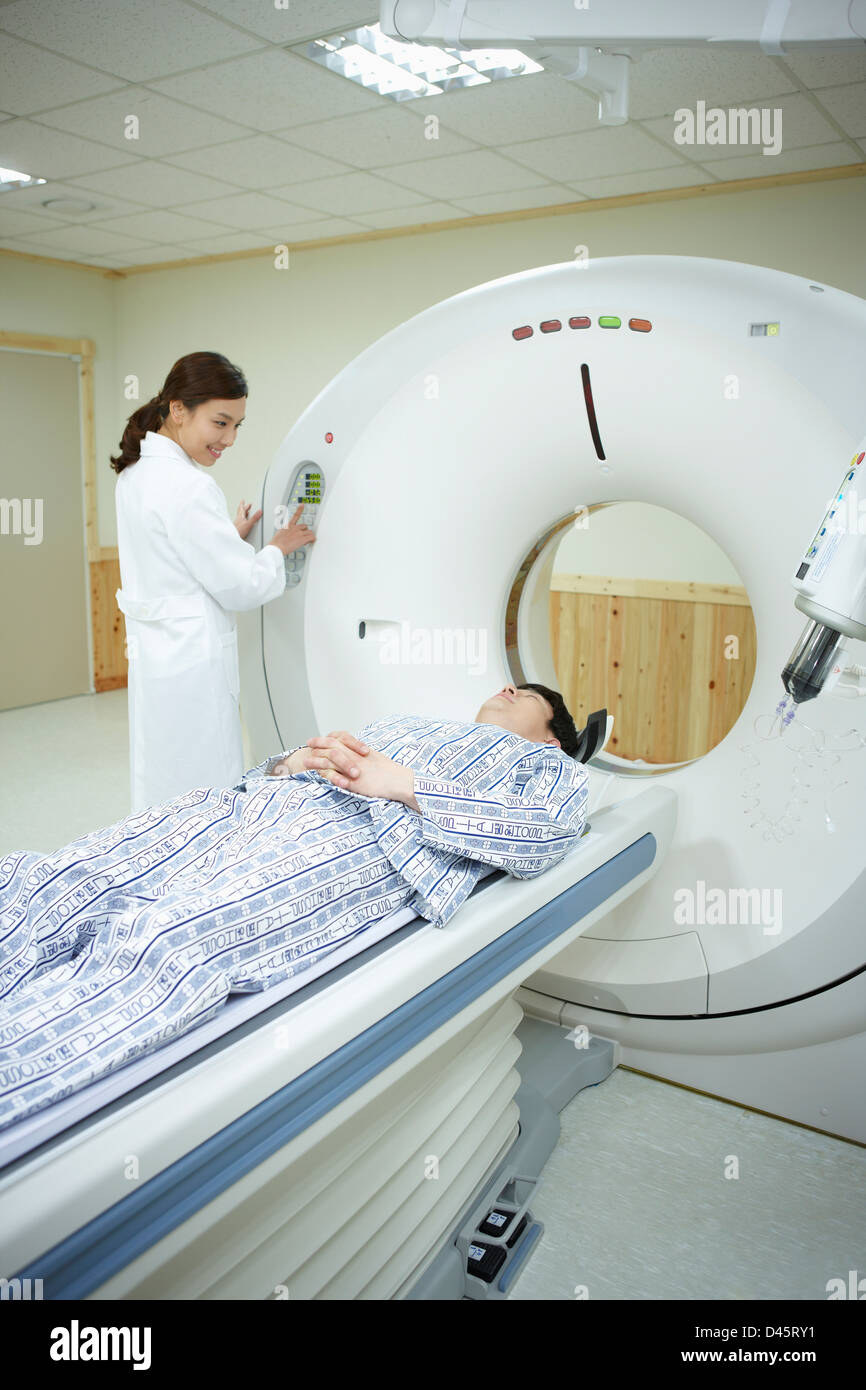 a doctor standing next to a patient lying on CT scanner bed Stock Photo ...