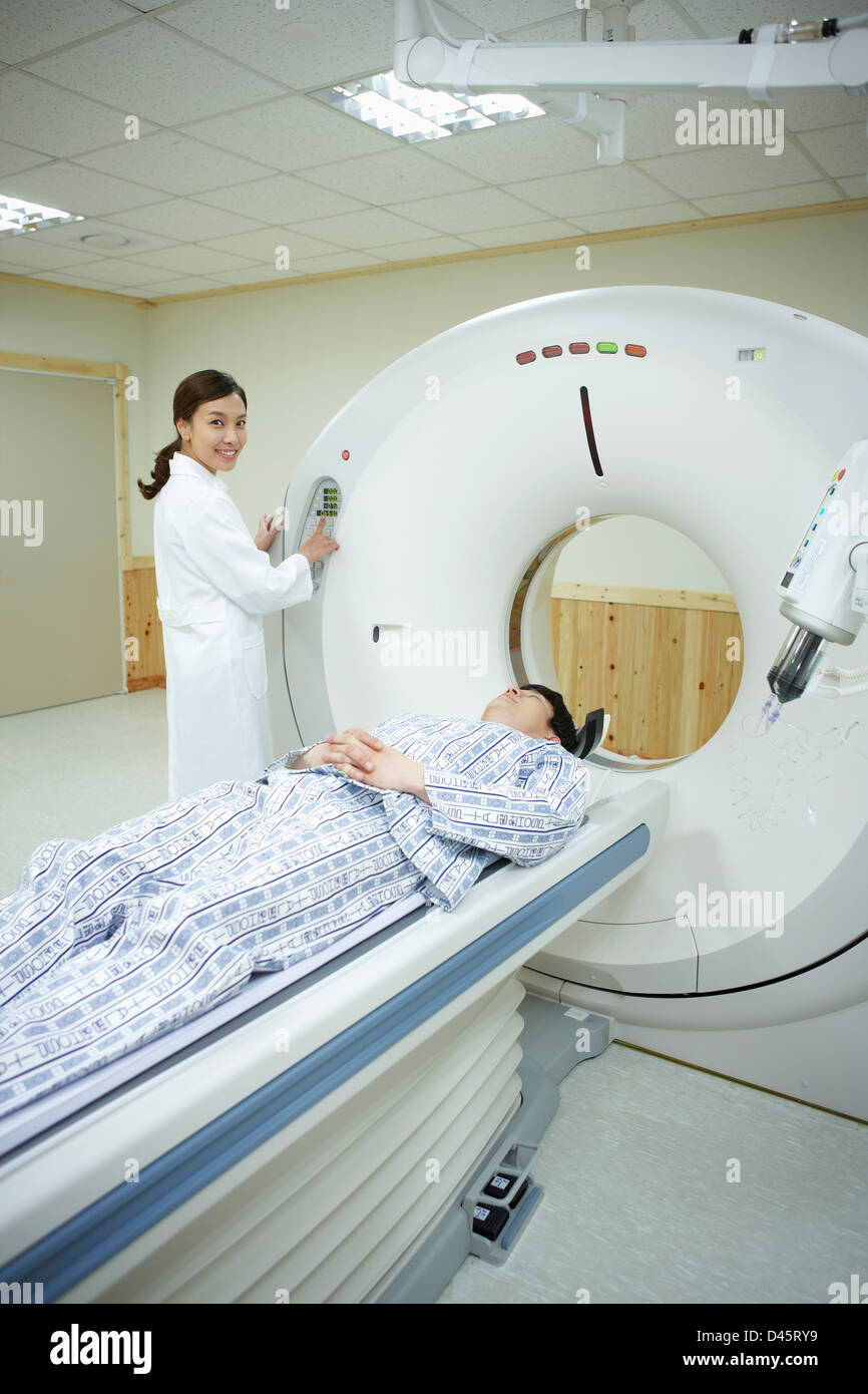 a doctor standing next to a patient lying on CT scanner bed Stock Photo ...