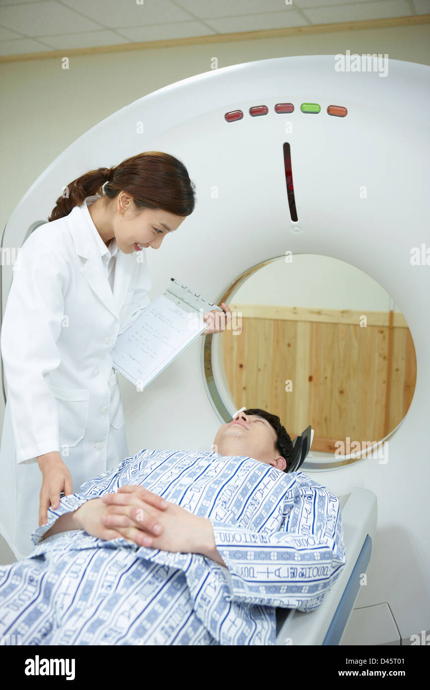 a doctor standing next to a patient lying on CT scanner bed Stock Photo ...