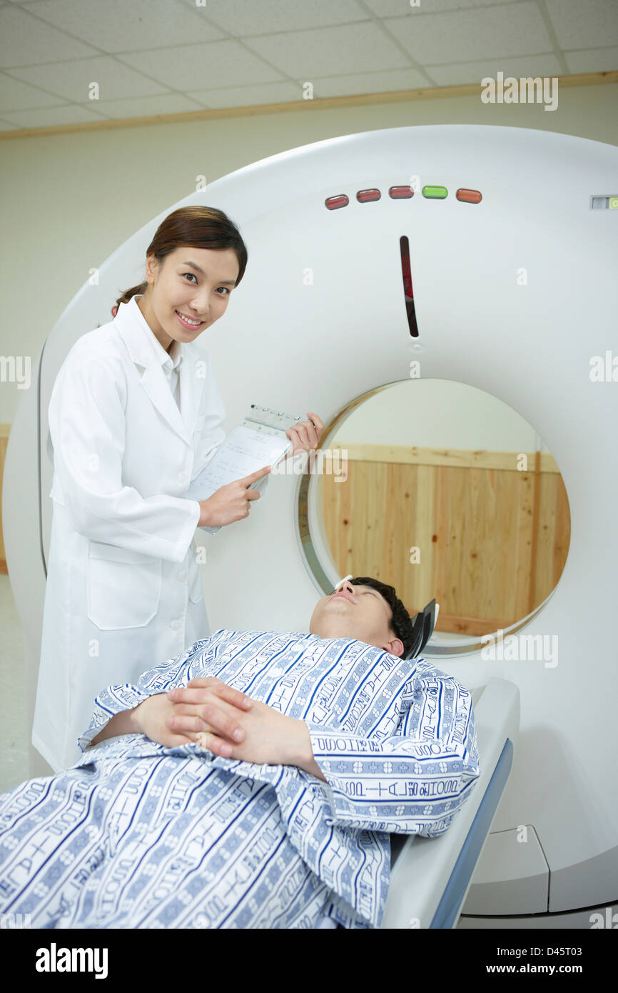 a doctor standing next to a patient lying on CT scanner bed Stock Photo ...