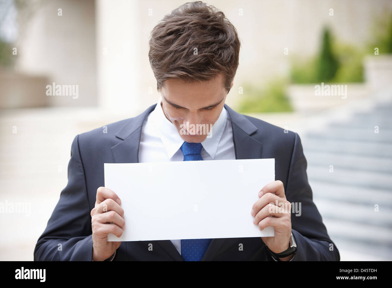a western businessman holding a white empty paper Stock Photo - Alamy