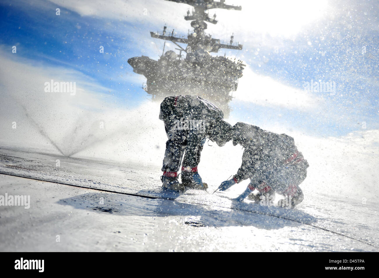 Sailors conduct a flight deck washdown aboard a U.S. Navy ship in the ...