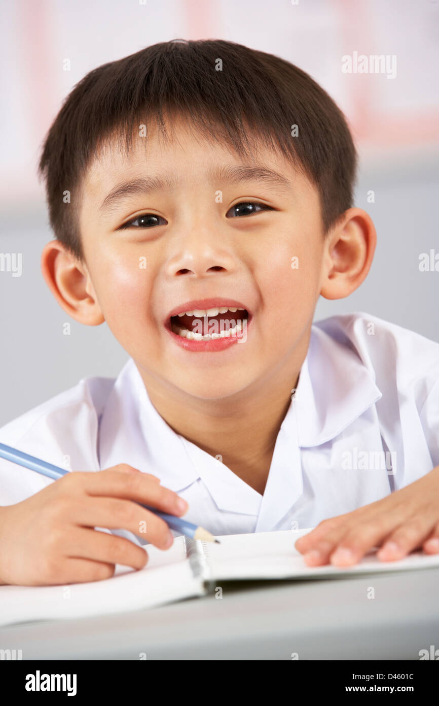 Male Student Working At Desk In Chinese School Classroom Stock Photo ...
