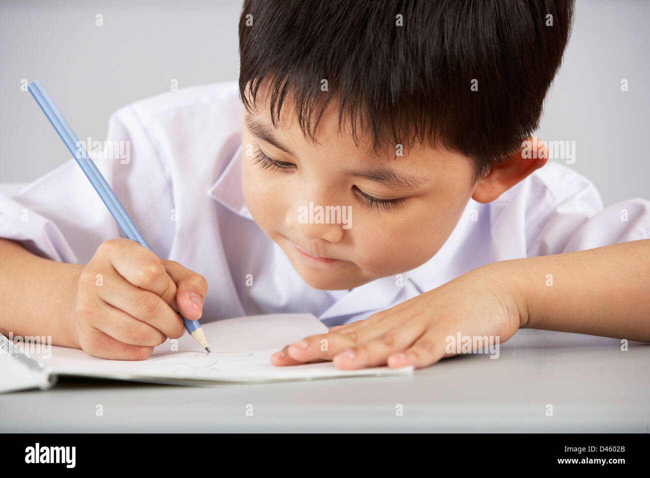 Male Student Working At Desk In Chinese School Classroom Stock Photo ...