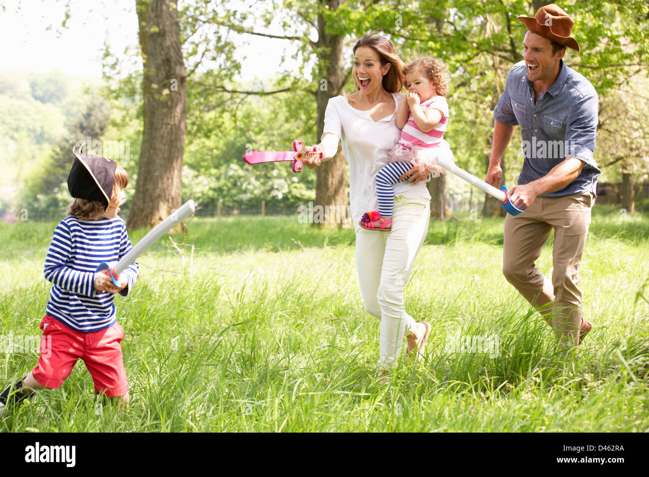 Parents Playing Exciting Adventure Game With Children In Summer Field ...