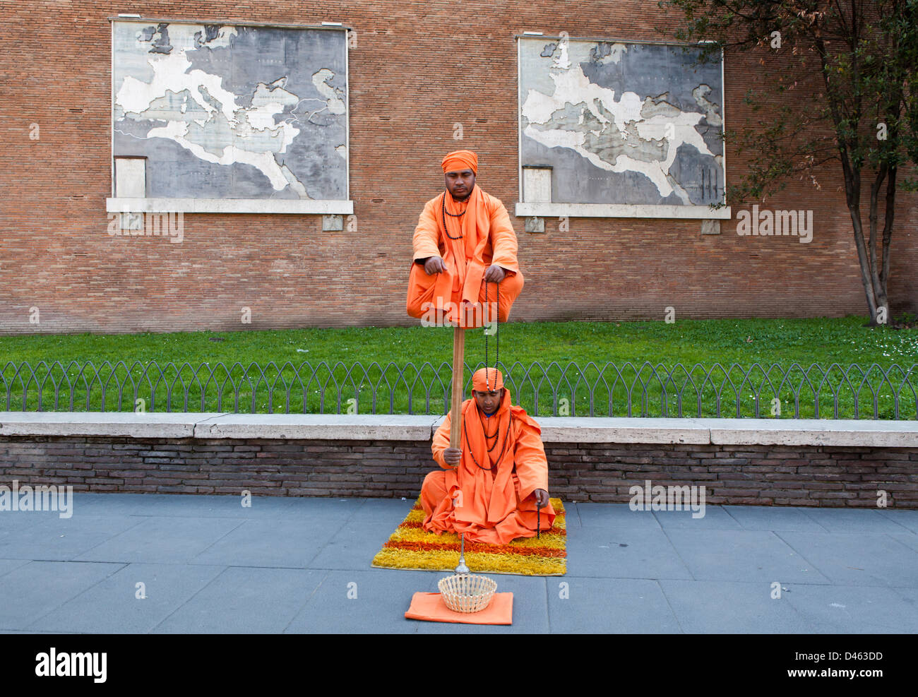 Two street performers dressed in orange monk's robes perform a ...