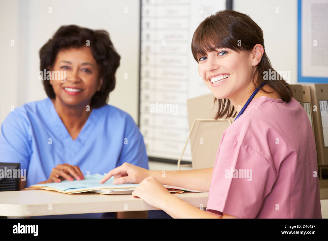 Two Nurses In Discussion At Nurses Station Stock Photo - Alamy