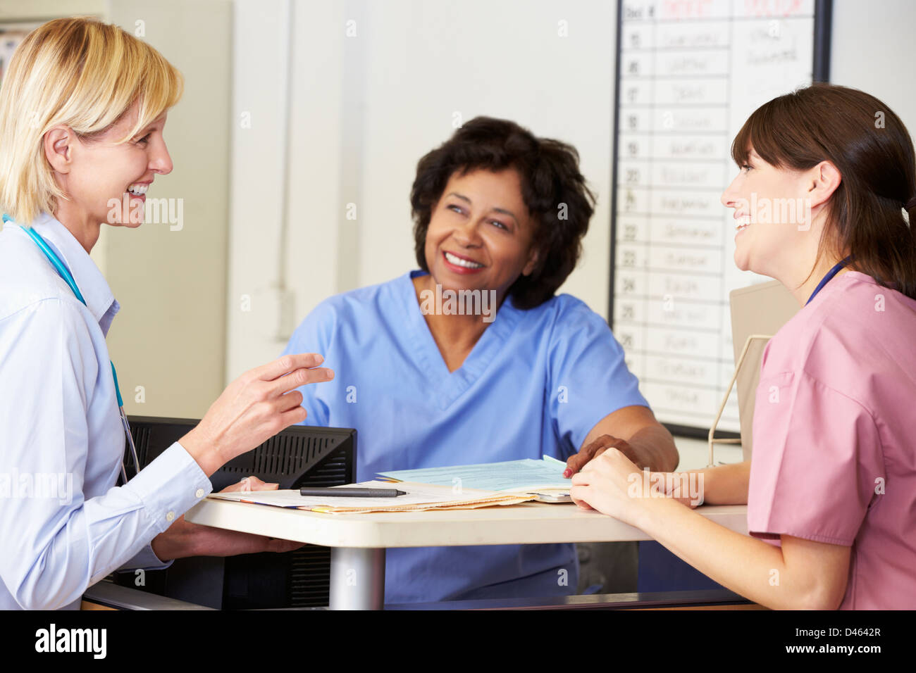 Doctor And Nurses In Discussion At Nurses Station Stock Photo - Alamy