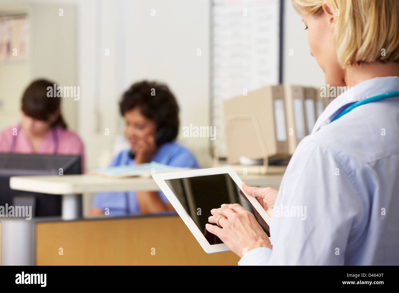 Female Doctor Using Digital Tablet At Nurses Station Stock Photo - Alamy