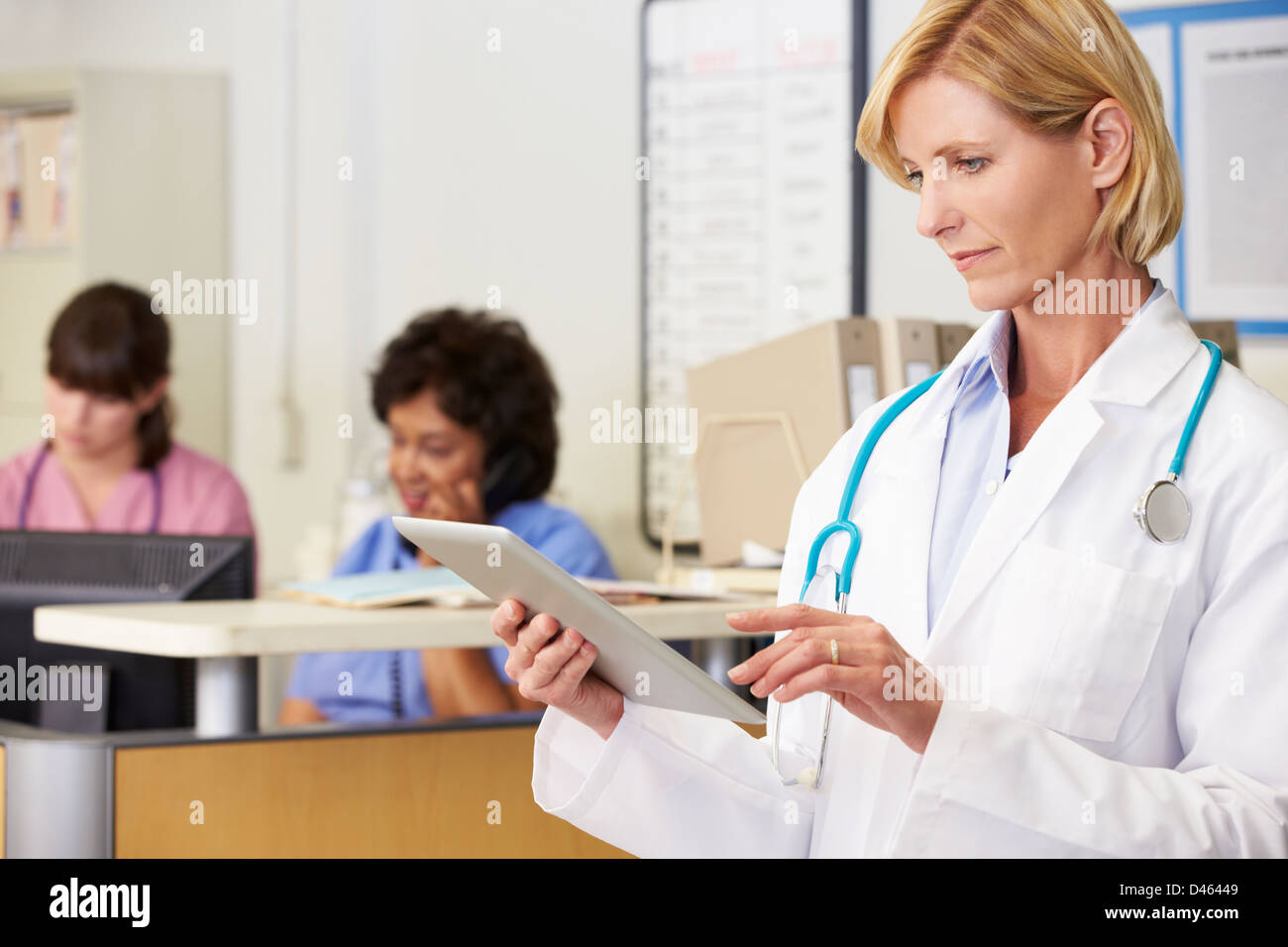 Female Doctor Using Digital Tablet At Nurses Station Stock Photo - Alamy