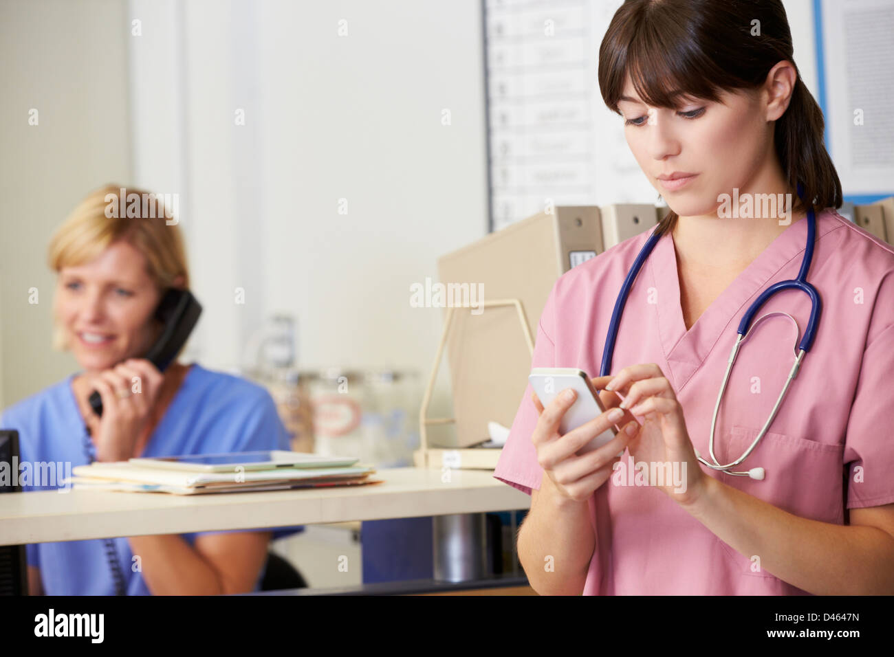Two Nurses Discussing Patient Notes At Nurses Station Stock Photo - Alamy