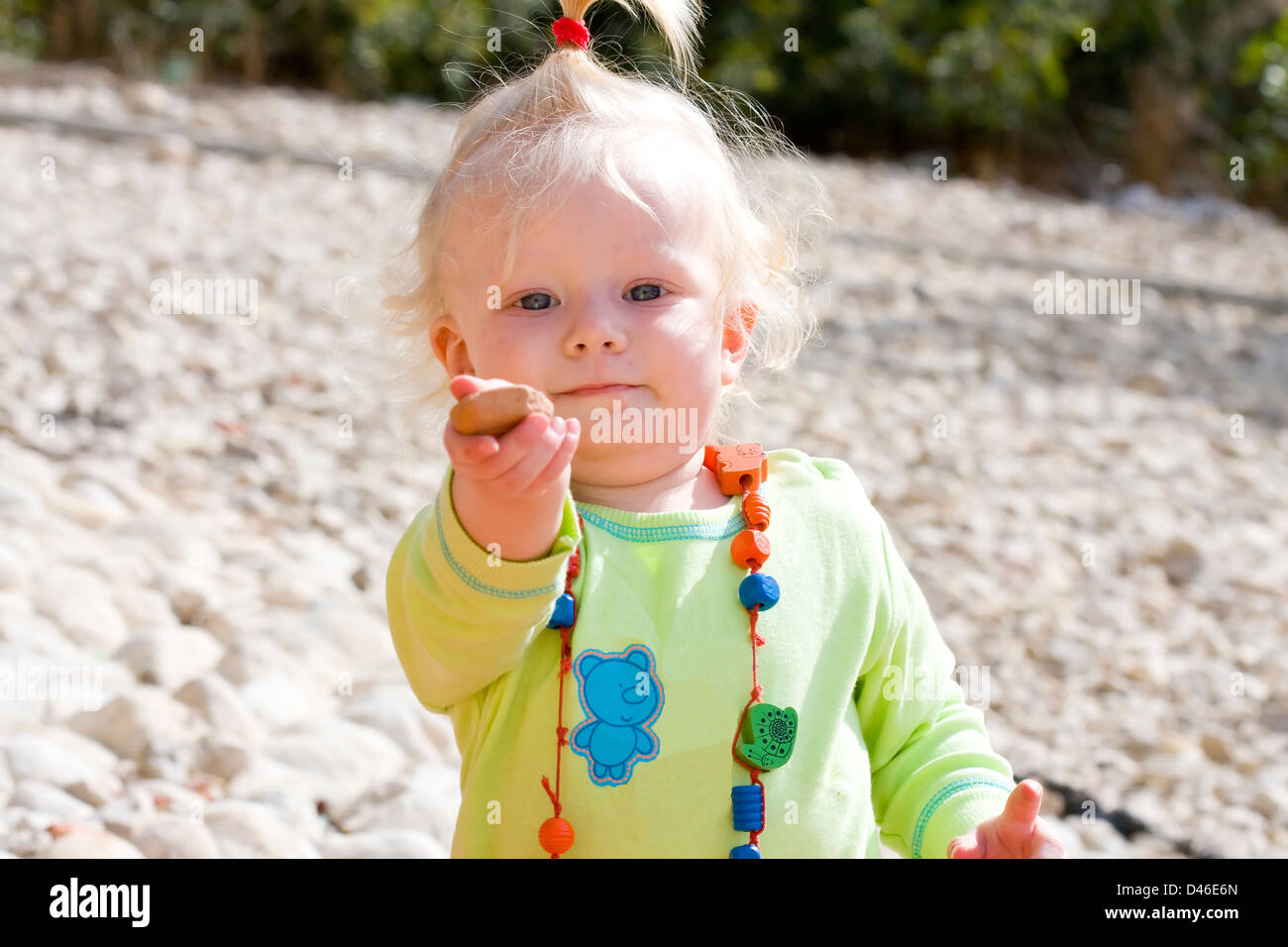 Cute baby girl holding out a pebble to play Stock Photo - Alamy
