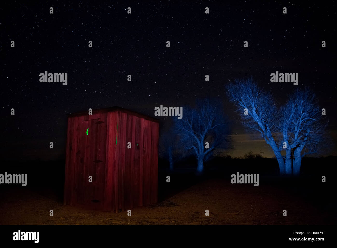 Old western outhouse in west Texas under a night time sky painted with ...