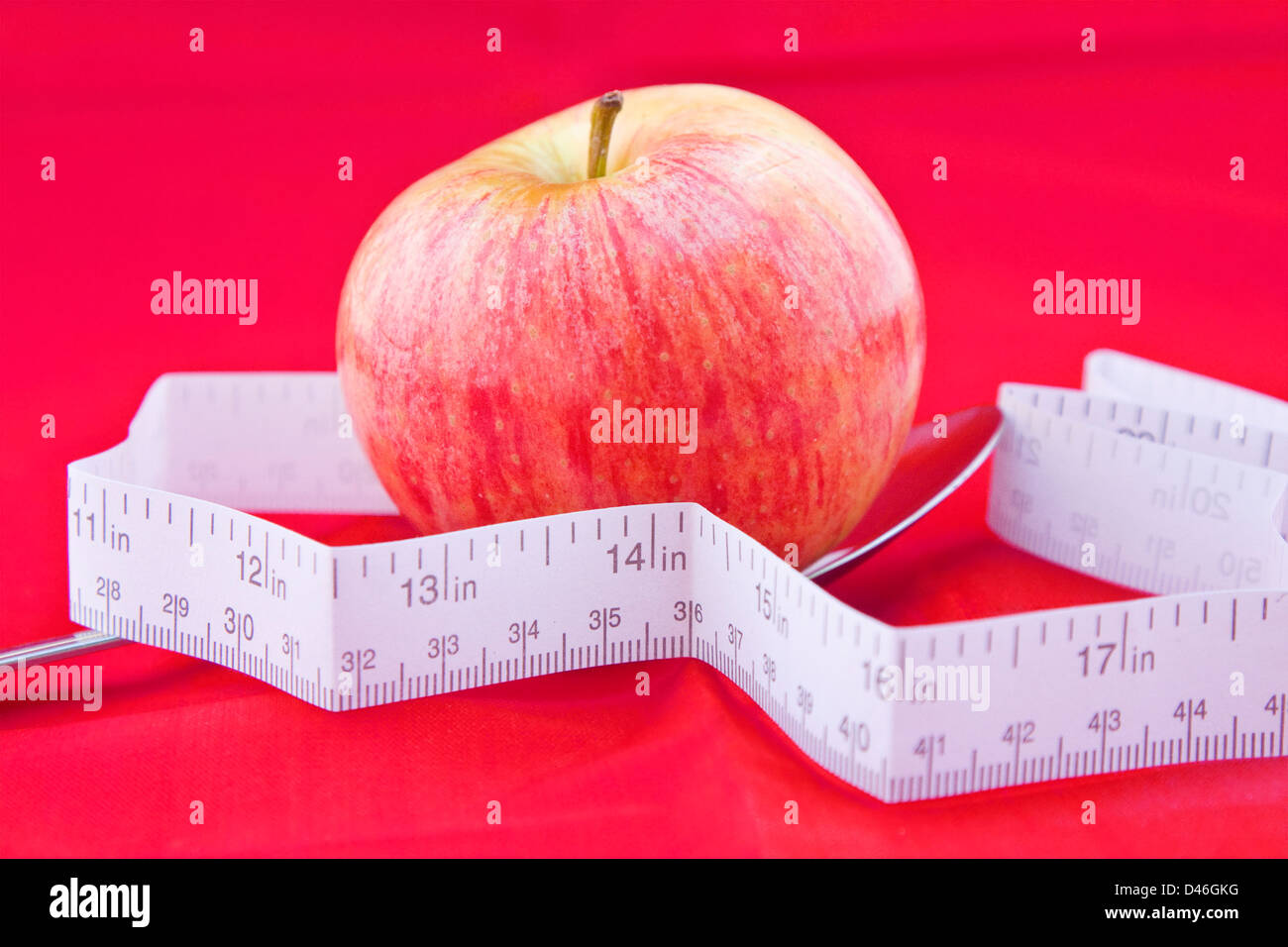 A red apple in a spoon with a paper meter around it standing for the ...