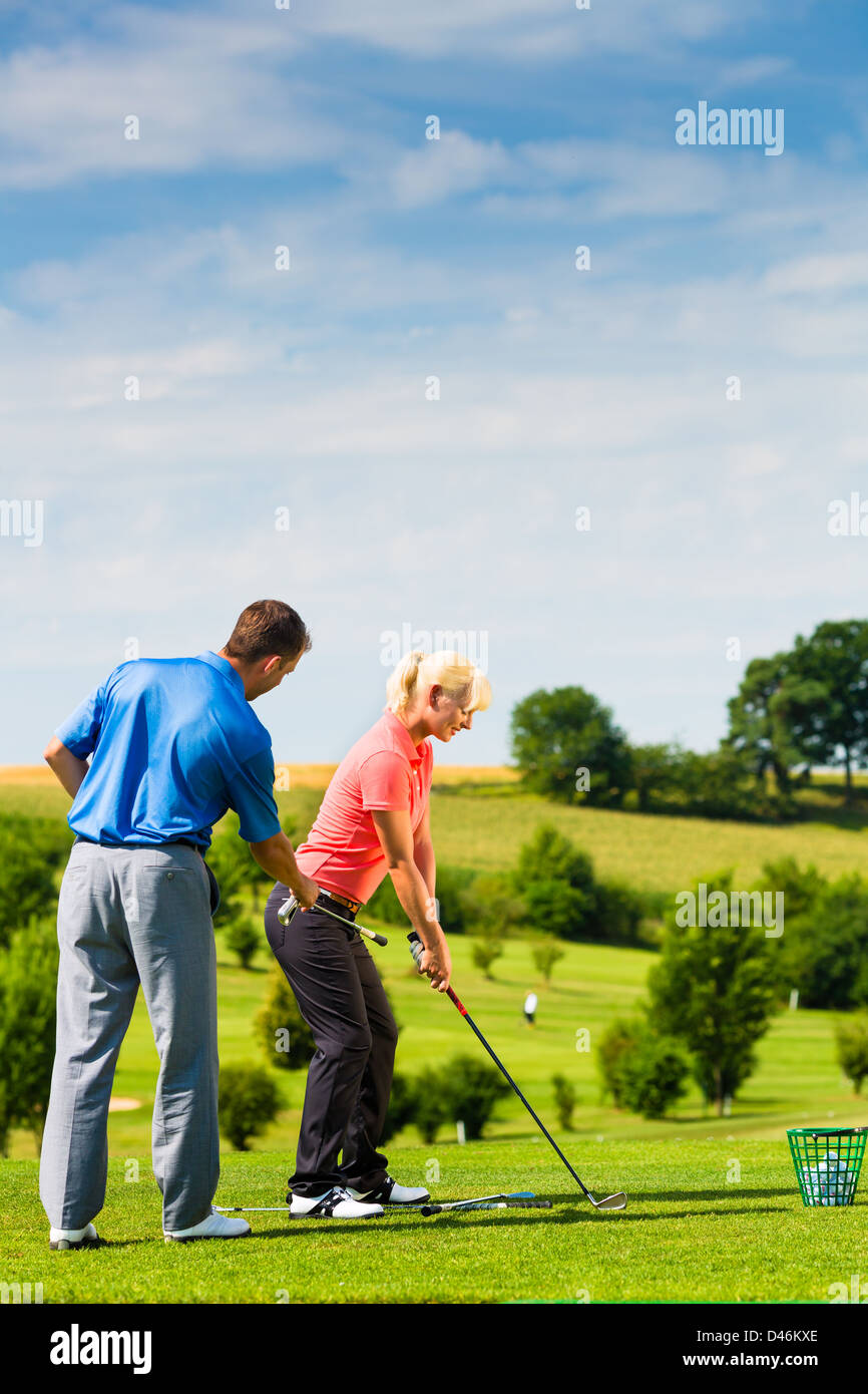 Young female golf player at Driving Range with a Golf Pro, she ...