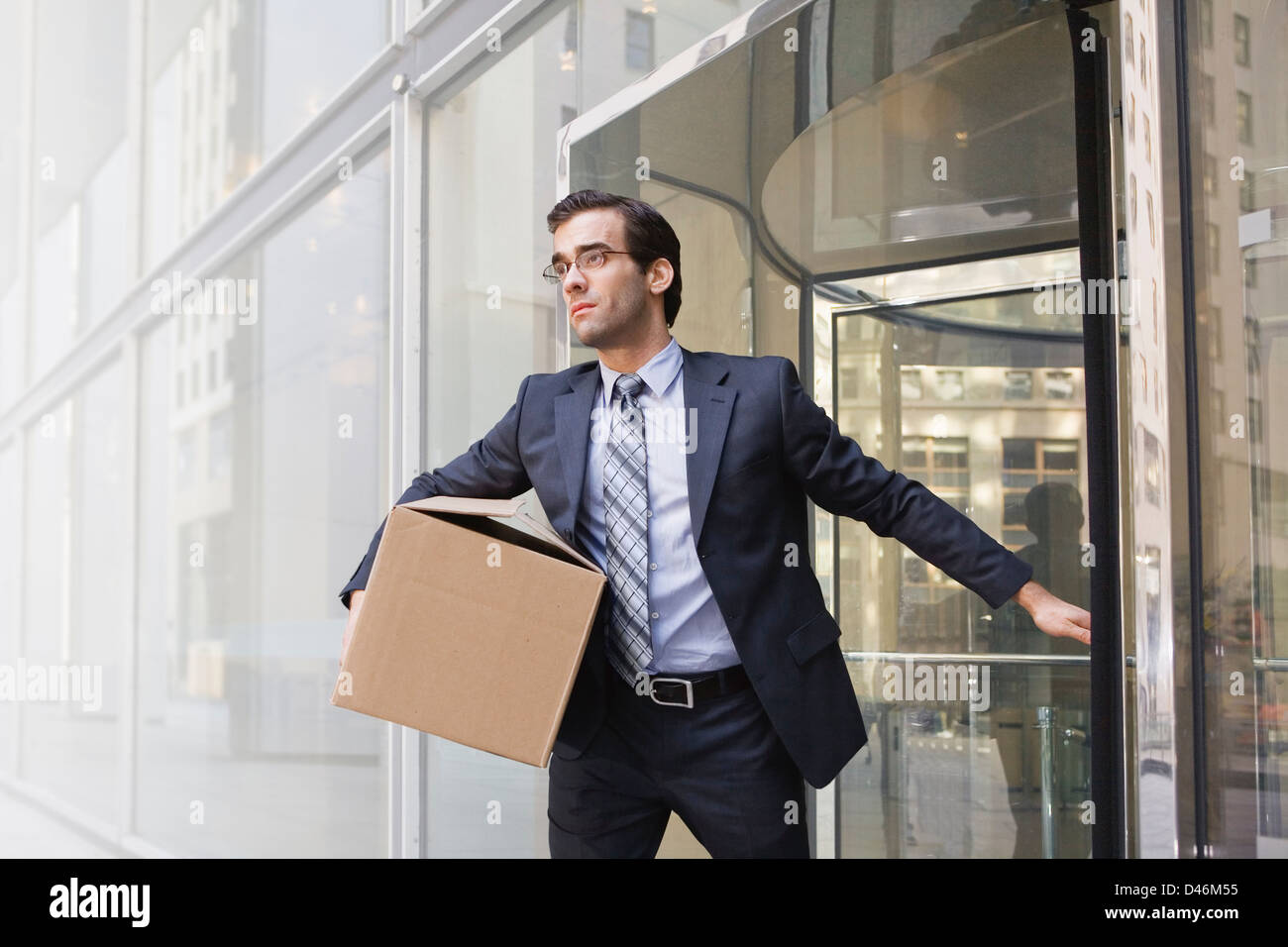 Wall Street trader leaving office building with box containing work ...