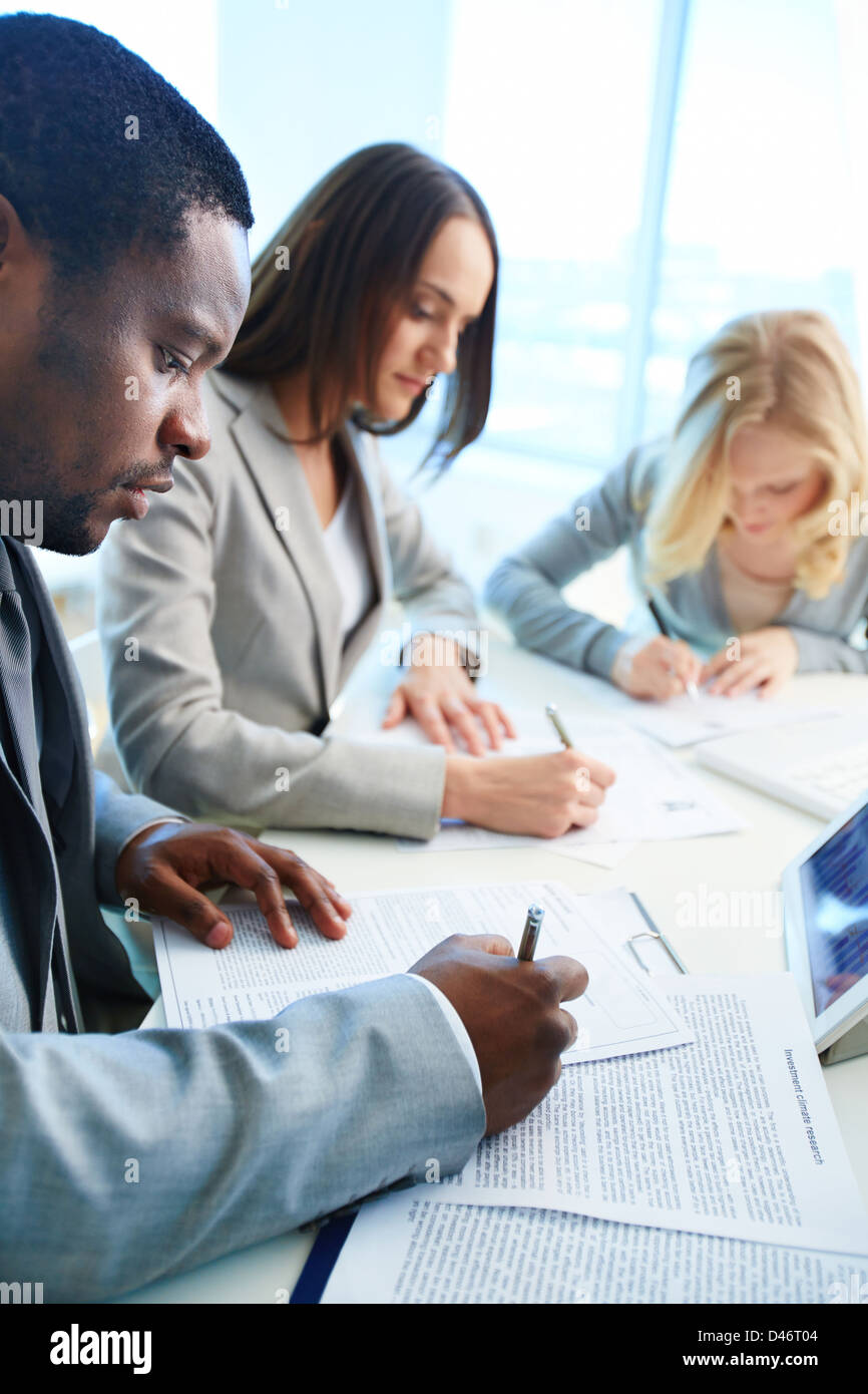Confident businessman signing papers with his two employees working on ...