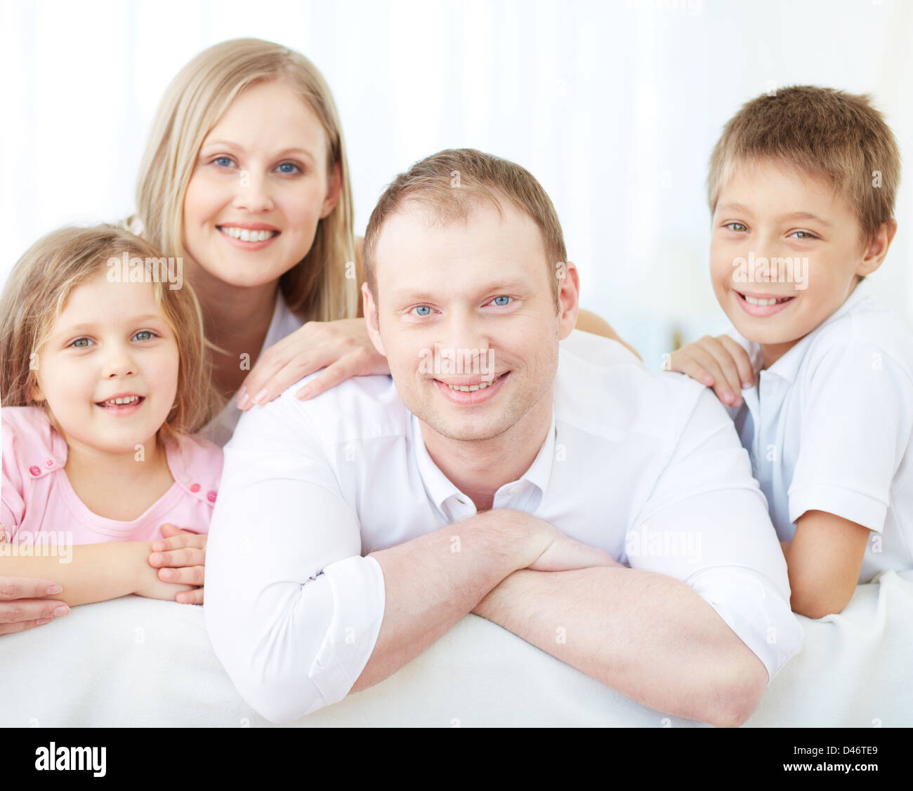 Portrait of happy parents with two children looking at camera at home ...