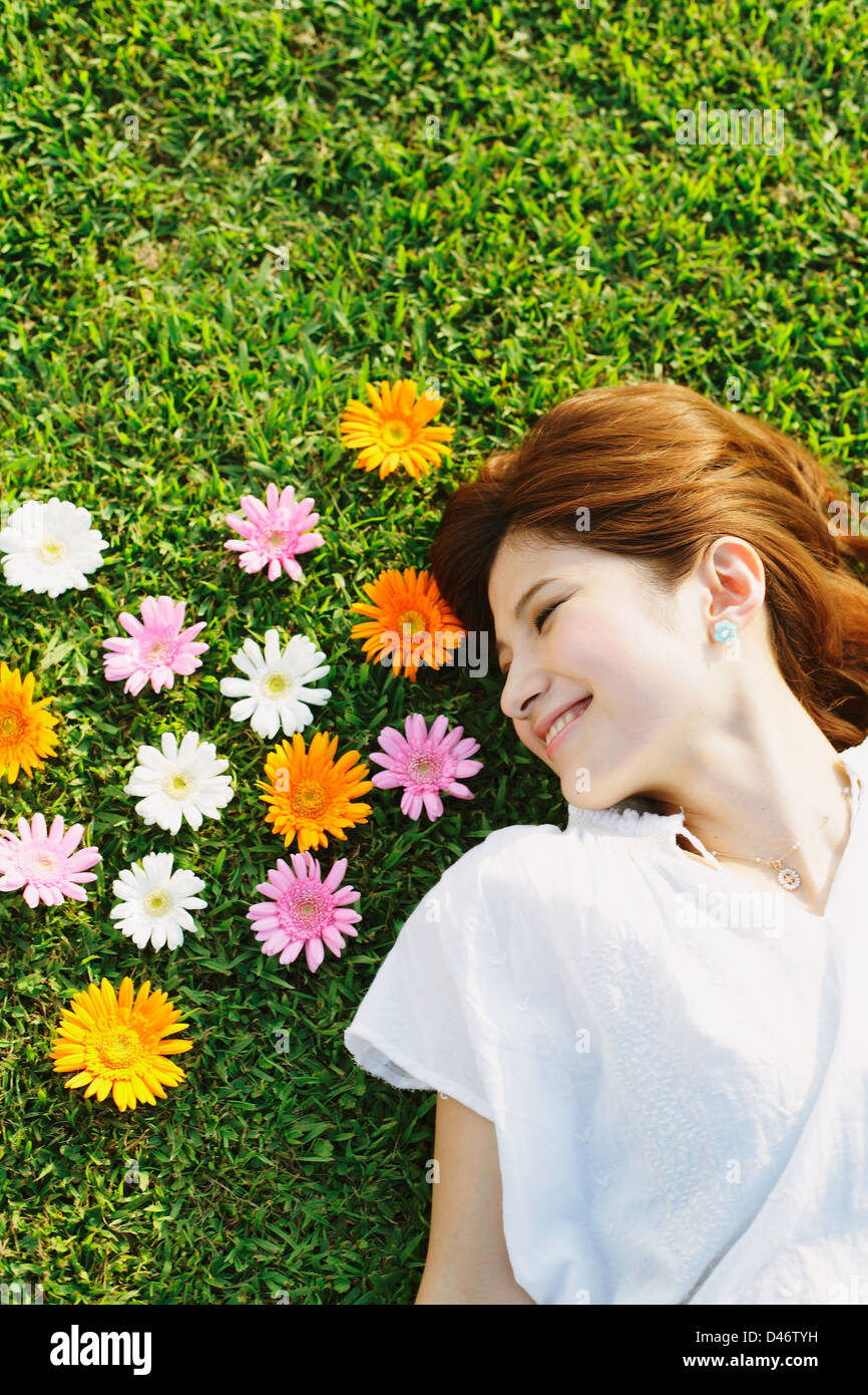 Woman With Flowers Laying Down On the Grass Stock Photo - Alamy