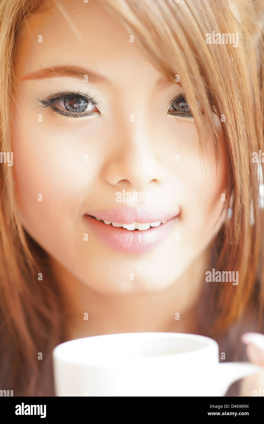 Closeup beautiful woman sitting in cafe holding and drinking coffee ...