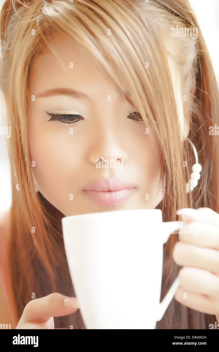 Closeup beautiful woman sitting in cafe holding and drinking coffee ...