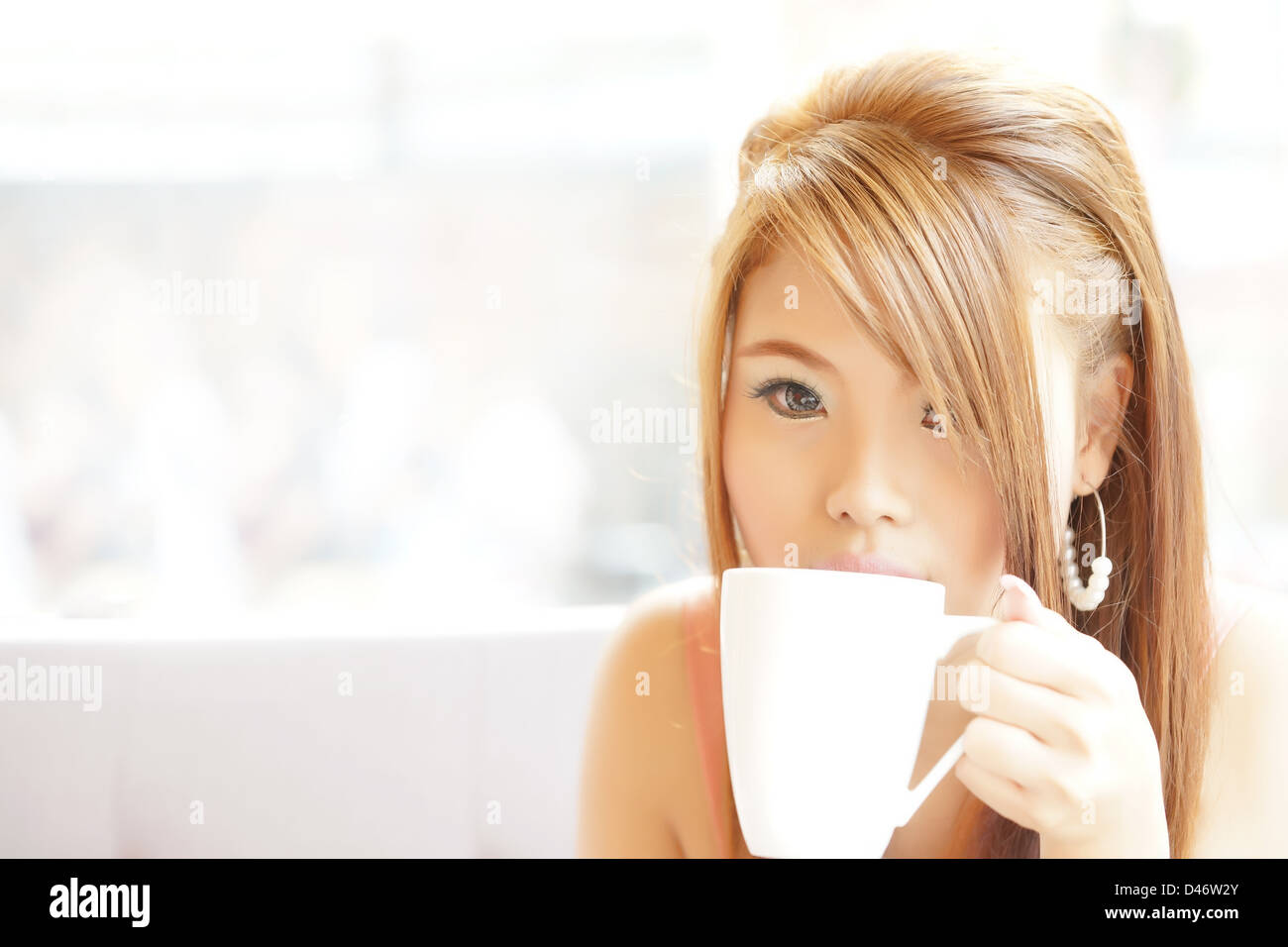 Closeup beautiful woman sitting in cafe holding and drinking coffee ...