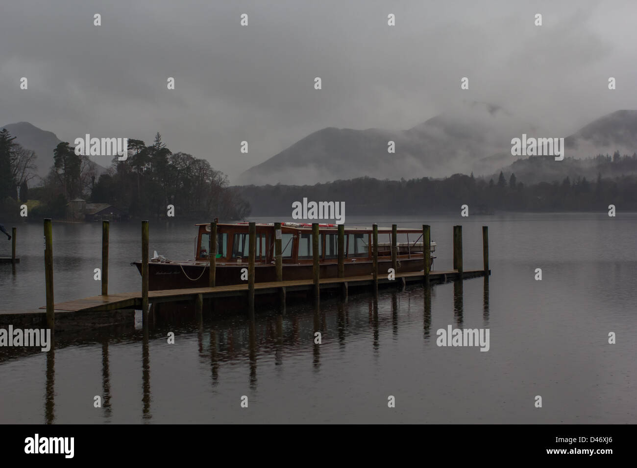 A Derwent Water launch alongside a wooden jetty during rain and low ...