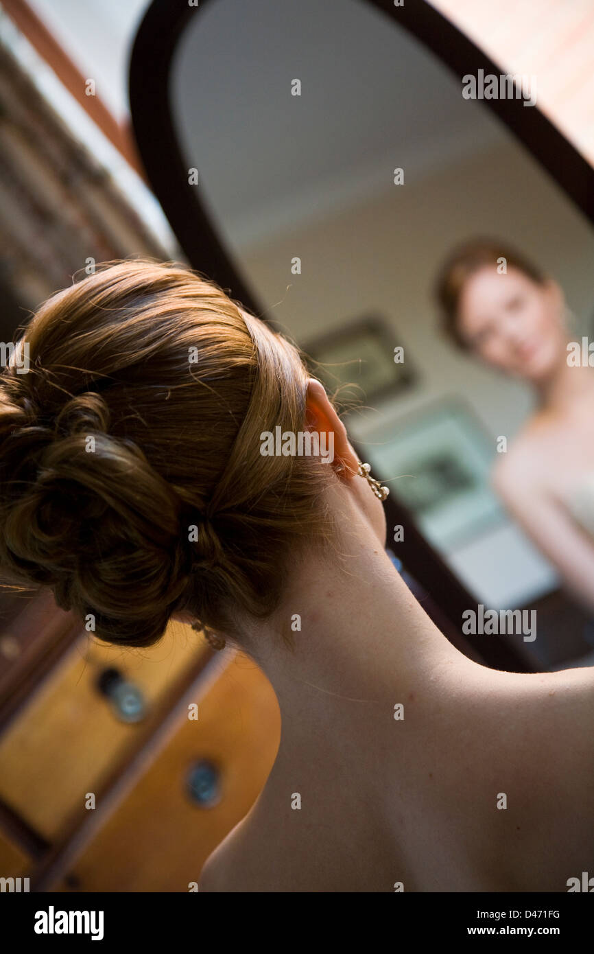 Back view reflected in oval full length mirror of red haired bride in ...