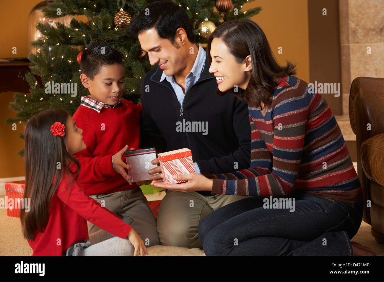 Family Opening Presents In Front Of Christmas Tree Stock Photo - Alamy