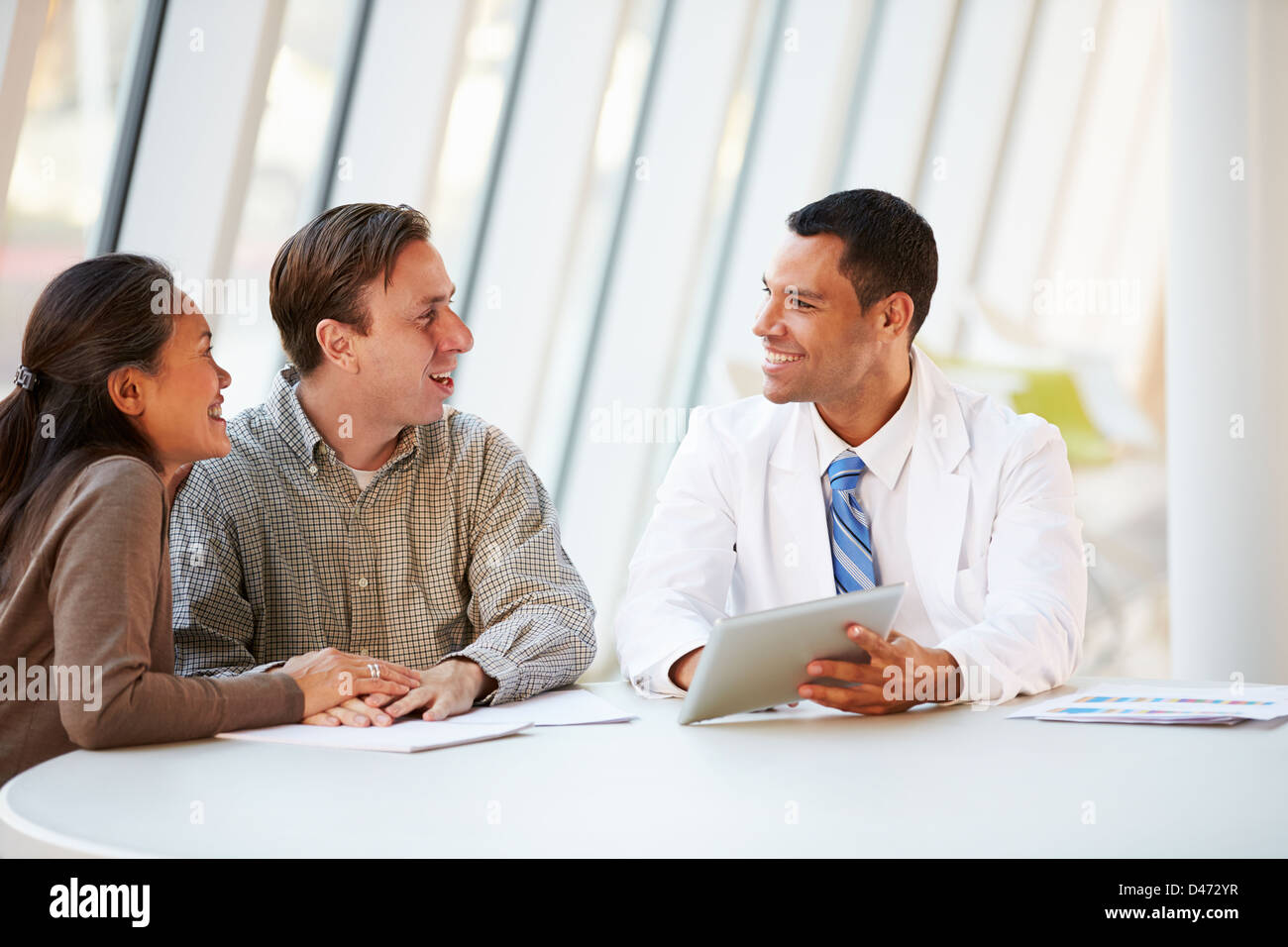 Doctor Using Tablet Computer Discussing Treatment With Patients Stock ...
