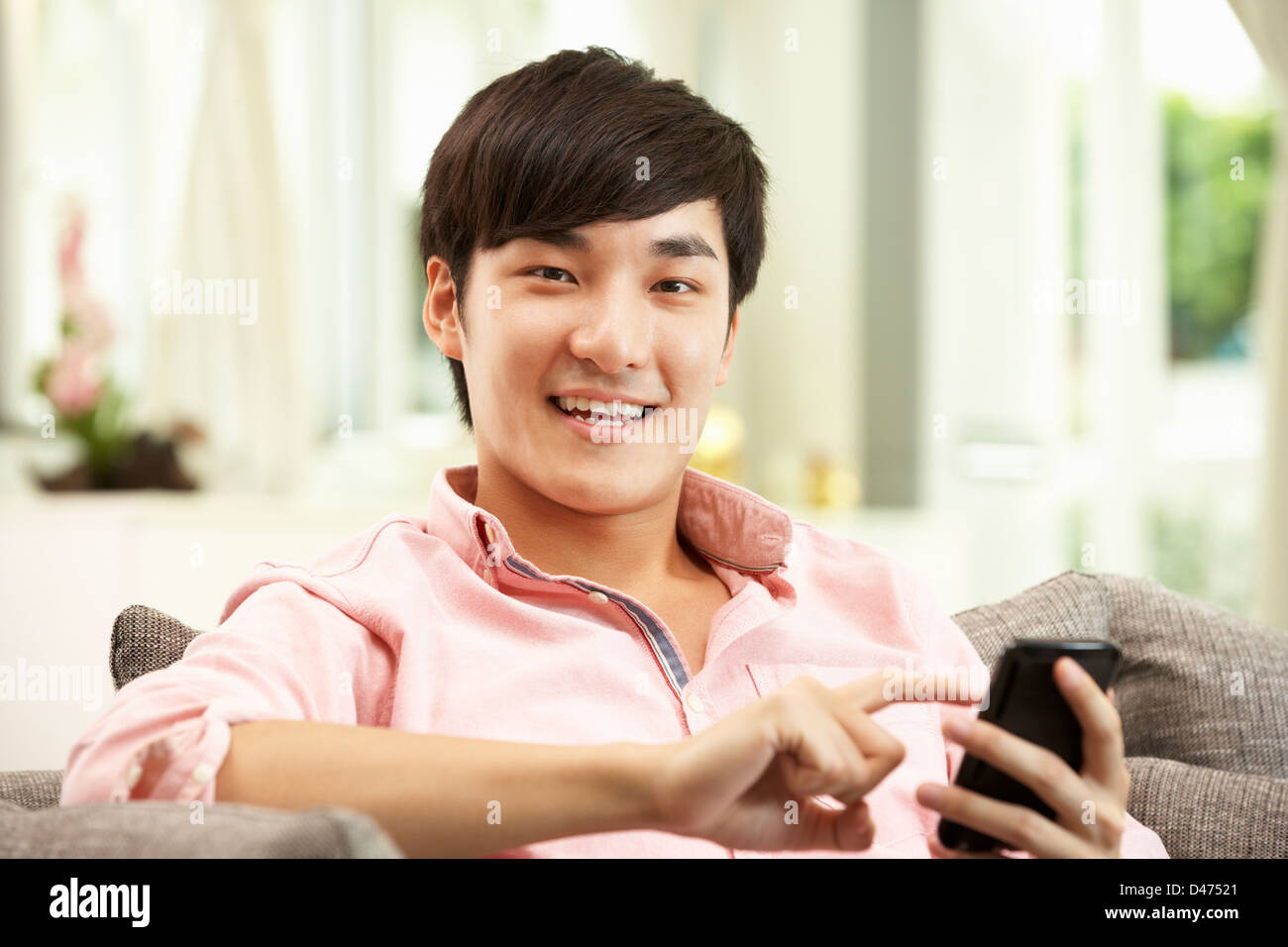 Young Chinese Man Using Mobile Phone On Sofa At Home Stock Photo - Alamy