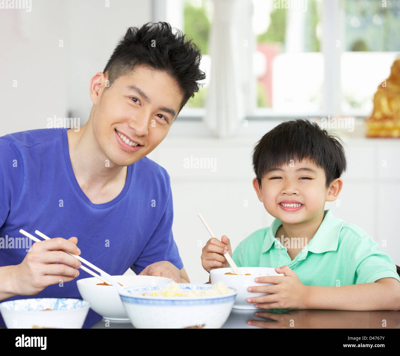 Chinese Father And Son Sitting At Home Eating A Meal Stock Photo - Alamy