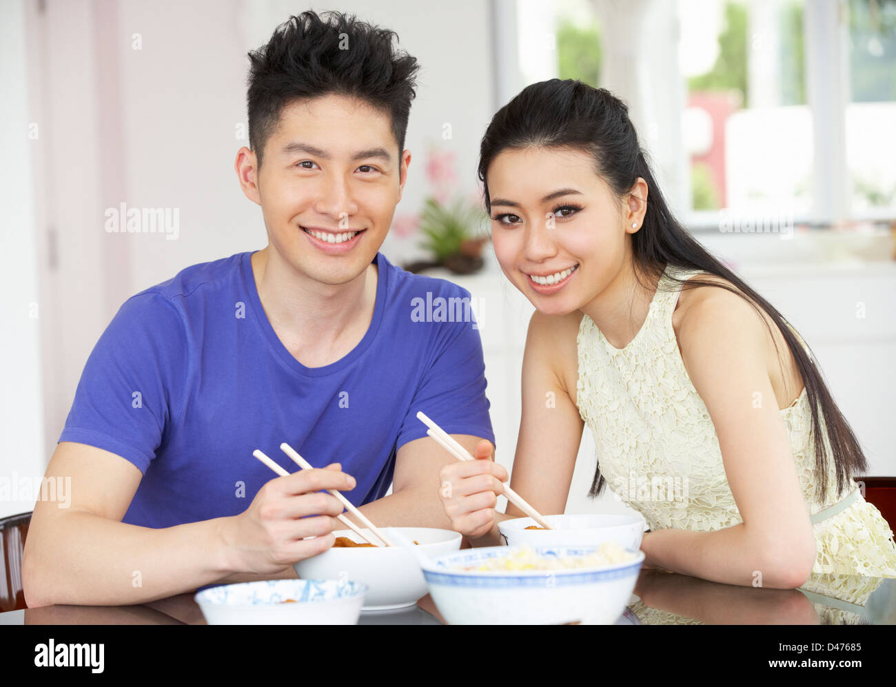 Young Chinese Couple Sitting At Home Eating Meal Stock Photo - Alamy