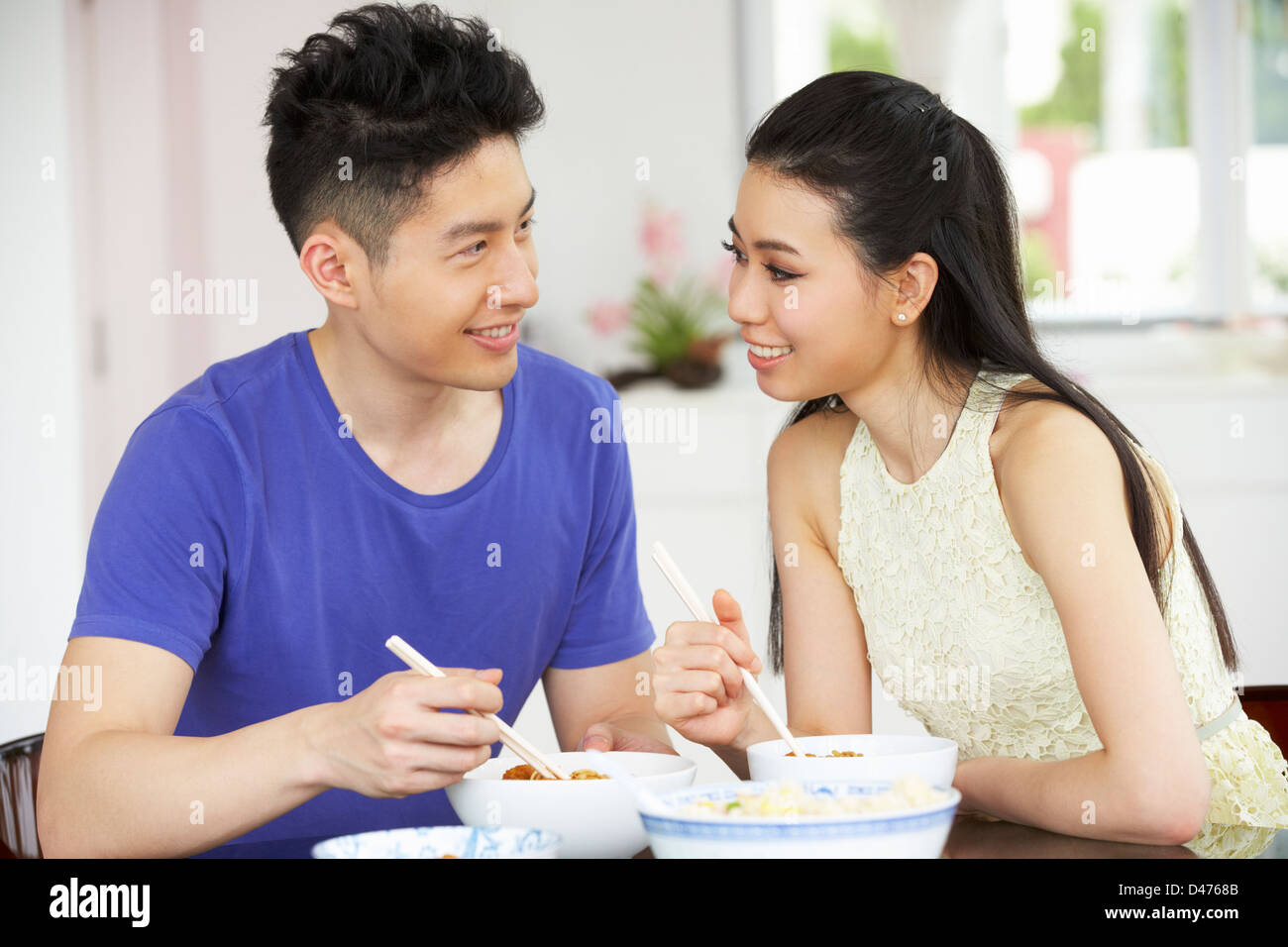 Young Chinese Couple Sitting At Home Eating Meal Stock Photo - Alamy